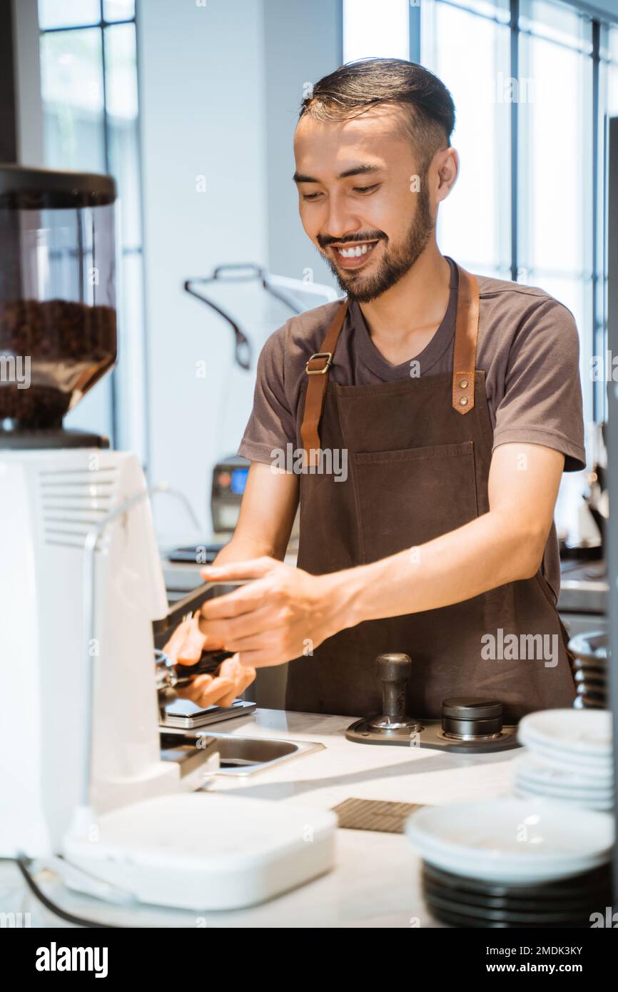 Male barista wearing apron makes coffee at the barista table Stock ...