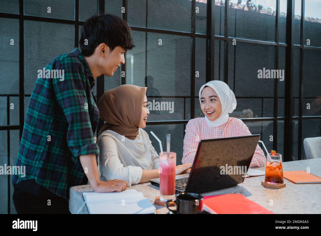 three young Asian people using a laptop and chatting Stock Photo - Alamy
