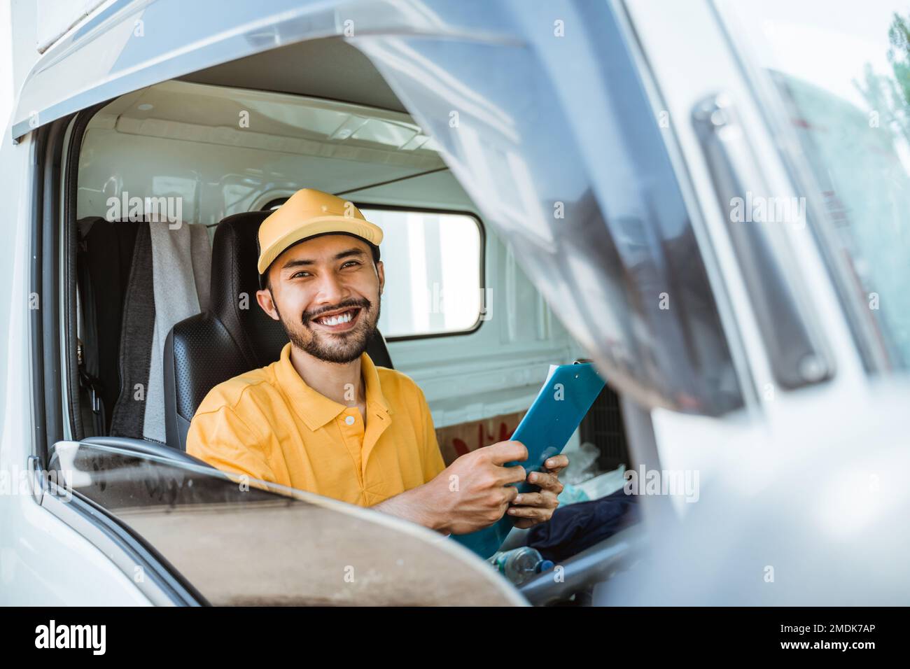 delivery man in yellow uniform smiling holding clipboard Stock Photo ...
