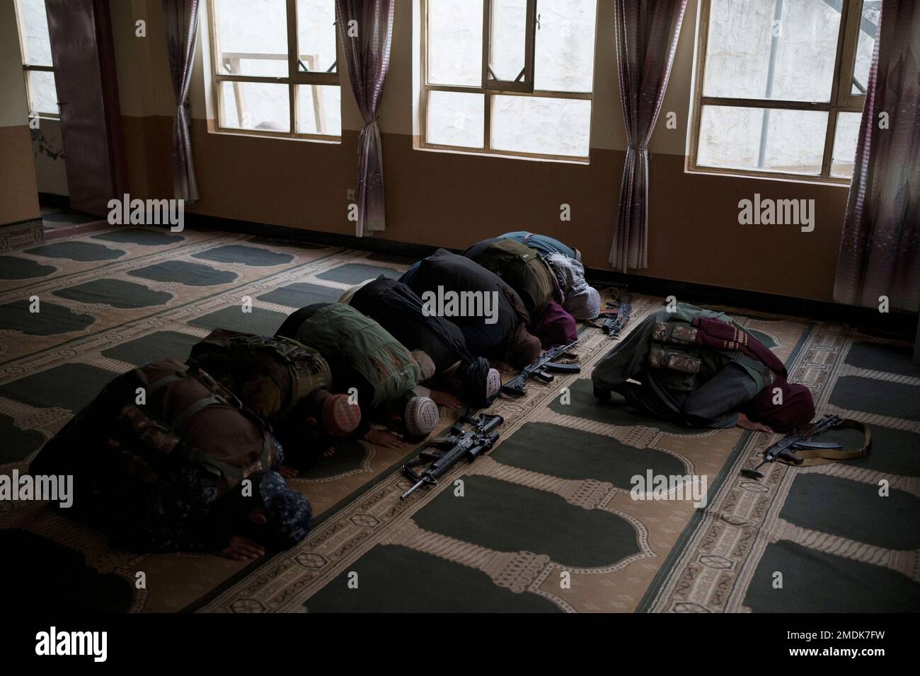 Taliban members lay their weapons down as they pray inside a mosque in ...
