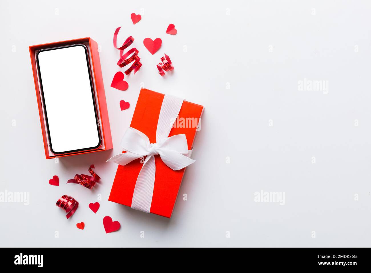 Opened gift box with ribbon and phone on color background, top view ...