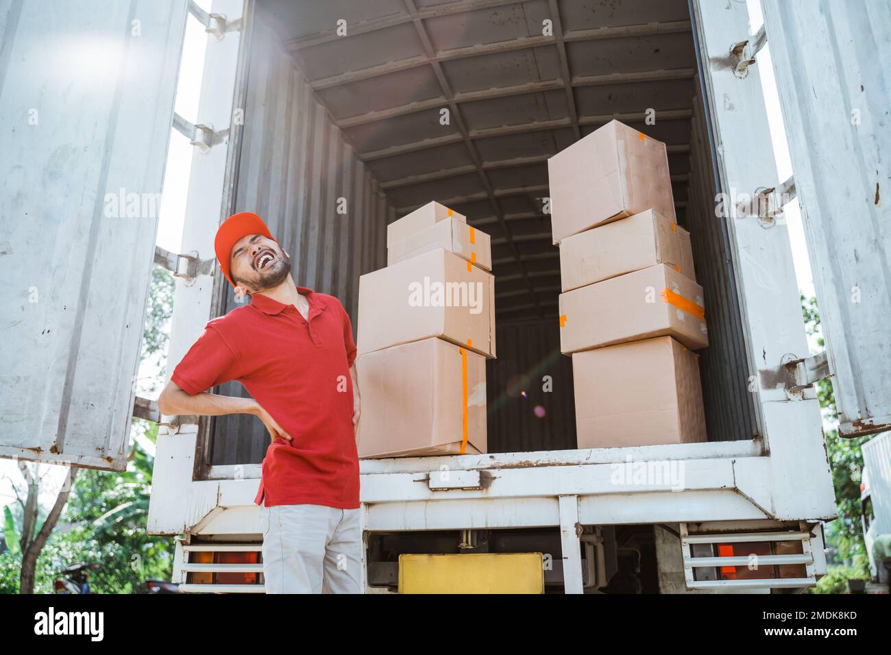 Delivery man having back pain while working with cardboard boxes Stock ...