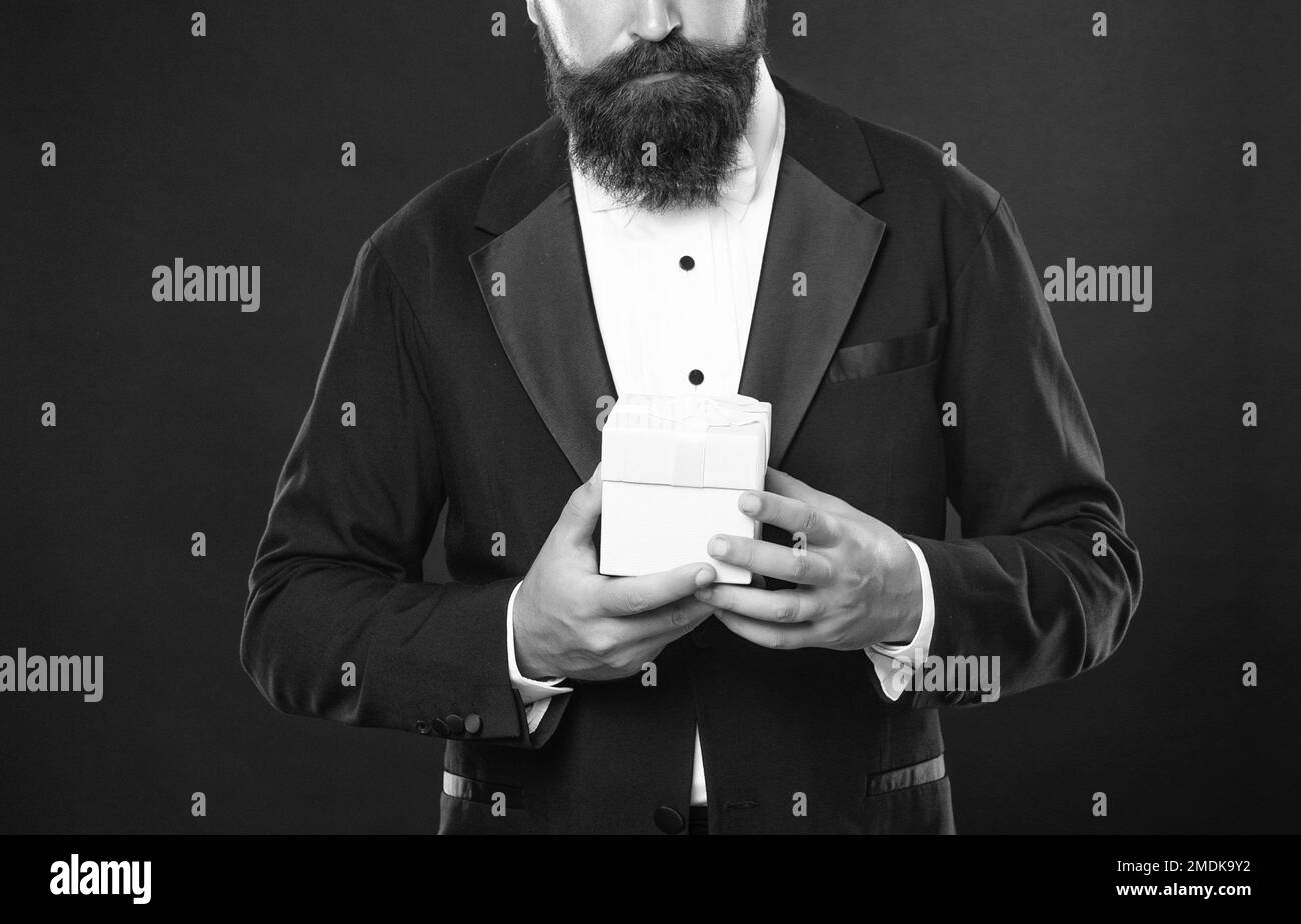 cropped man in tuxedo bow tie formalwear on black background with box ...