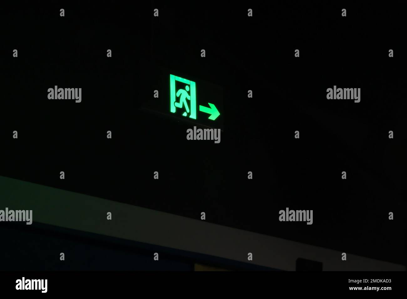 A luminescent green emergency exit sign with arrow in the dark Stock ...