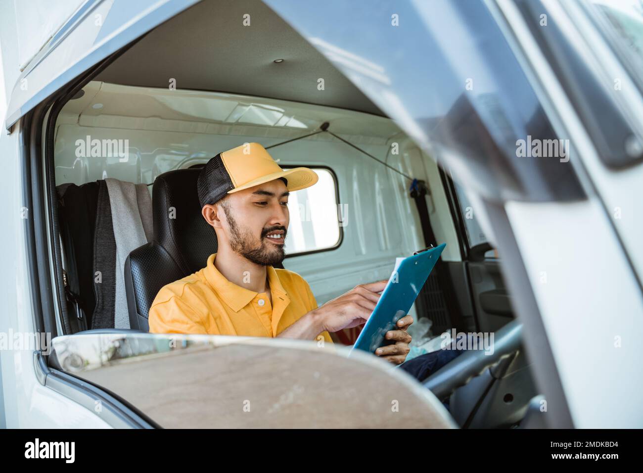 male driver in yellow uniform looking at clipboard to check Stock Photo ...