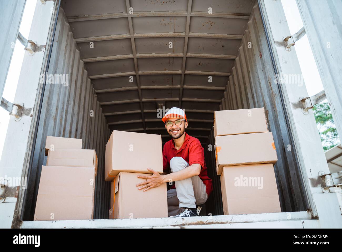 Smiling asian delivery man going to lift package box Stock Photo - Alamy