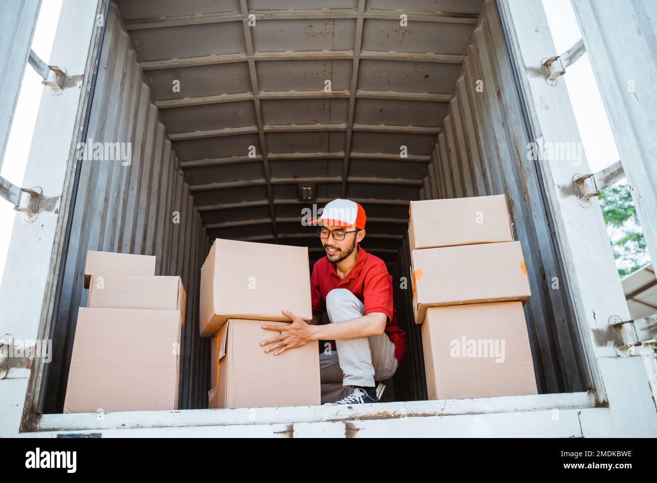 Asian delivery man stacking cardboard boxes of packages Stock Photo - Alamy
