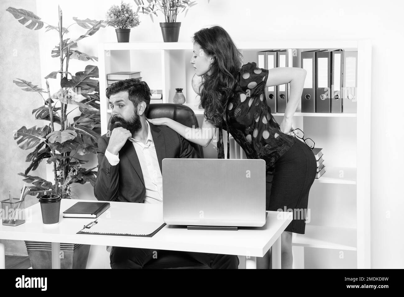 Flirting at work. Assistant flirting with manager sitting on desk ...