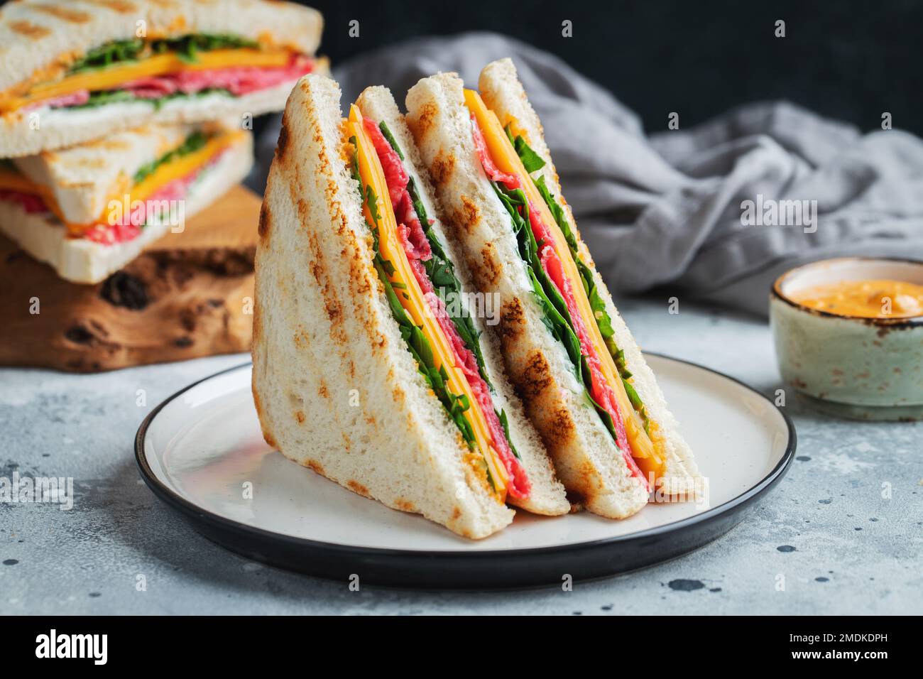 Two homemade sandwiches with sausage, cheese and arugula on a light ...