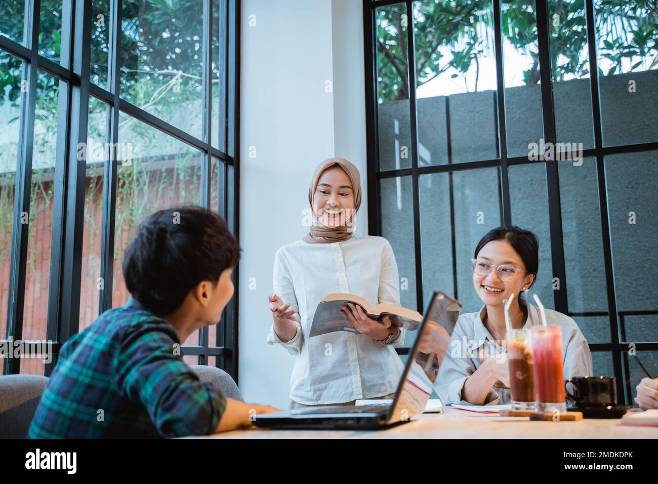 two girls discussing with their friends while doing assignments in ...