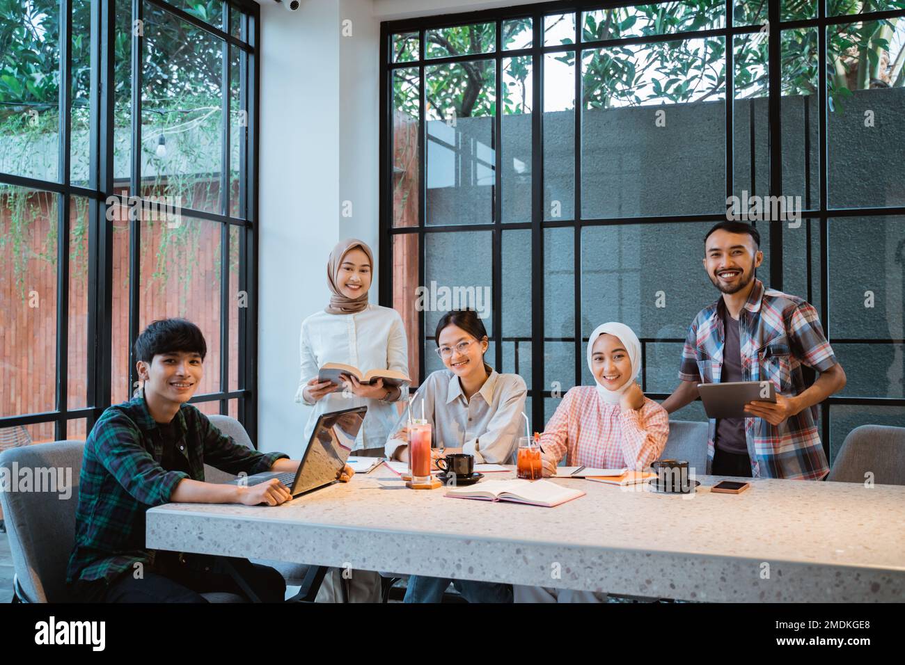 five young asian people smiling while doing assignment in library Stock ...