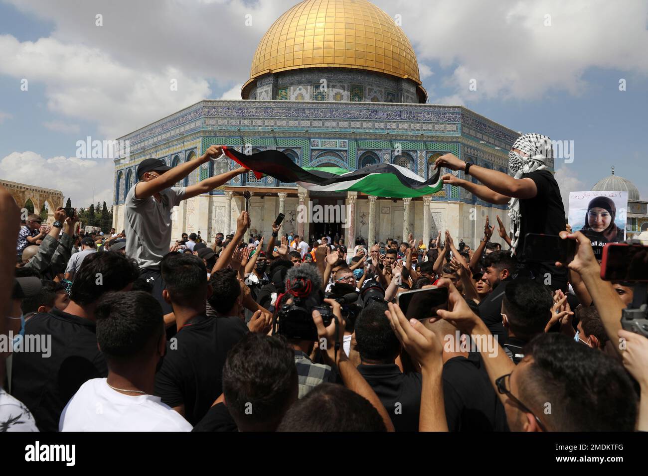 Protesters wave a Palestinian flag and one in the crowd holds a spoon ...