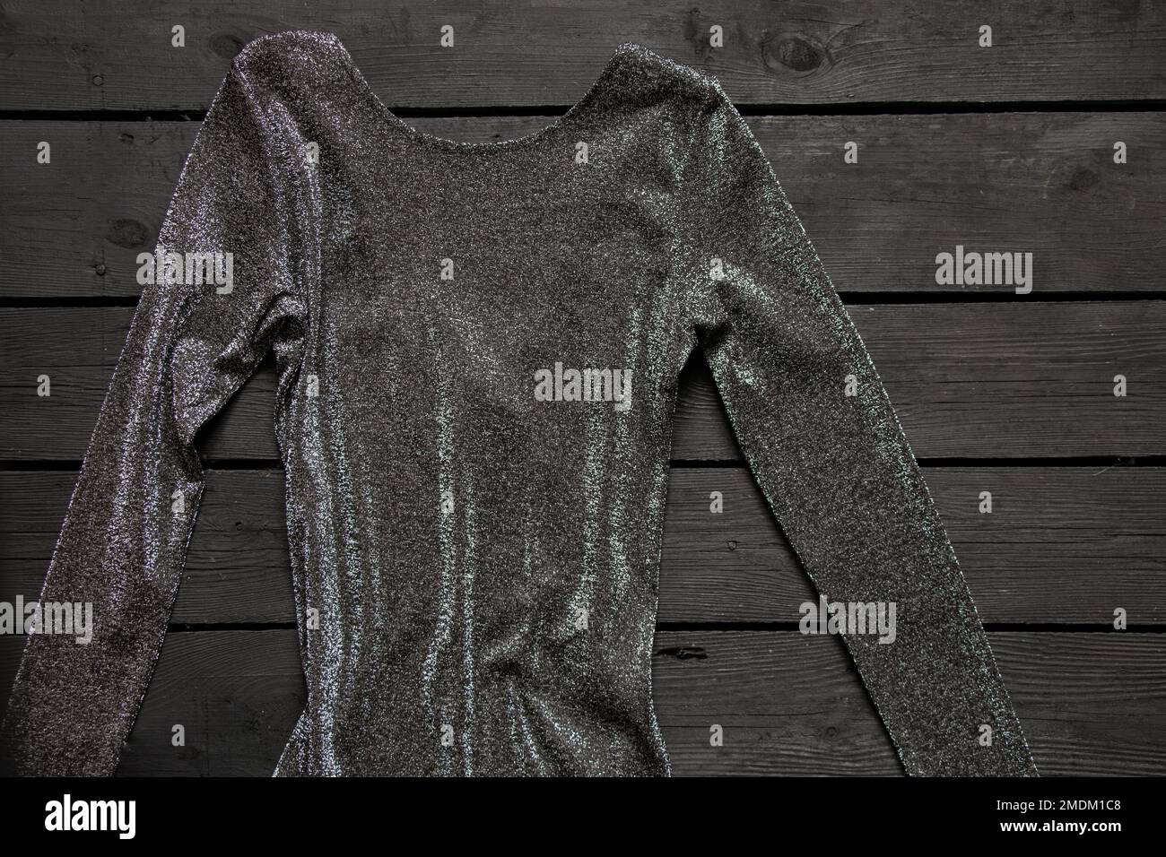 black evening classic dress with sequins lies on a black wooden table ...