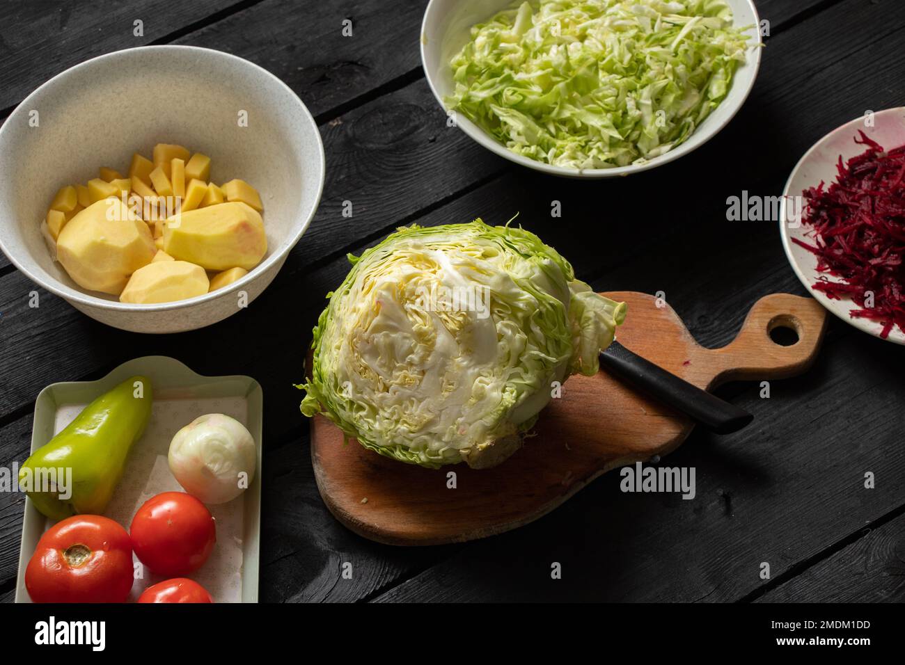 cabbage potatoes pepper tomato beetle are slicing on the table, cooking ...
