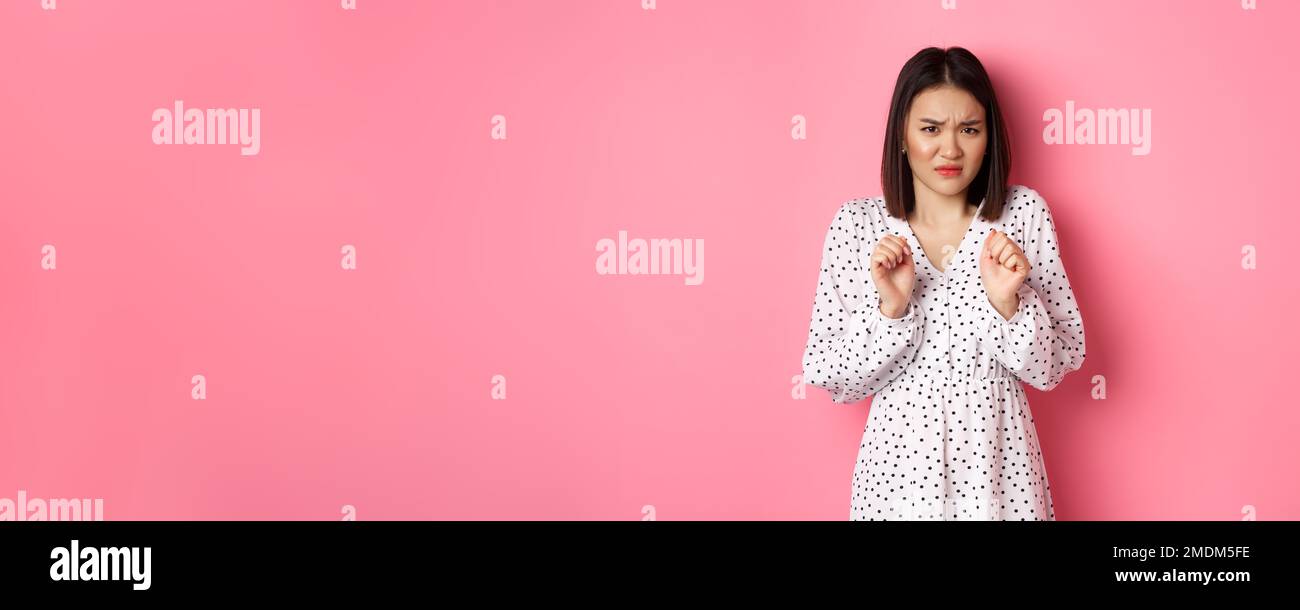 Disgusted asian woman staring with aversion and dislike, frowning and ...