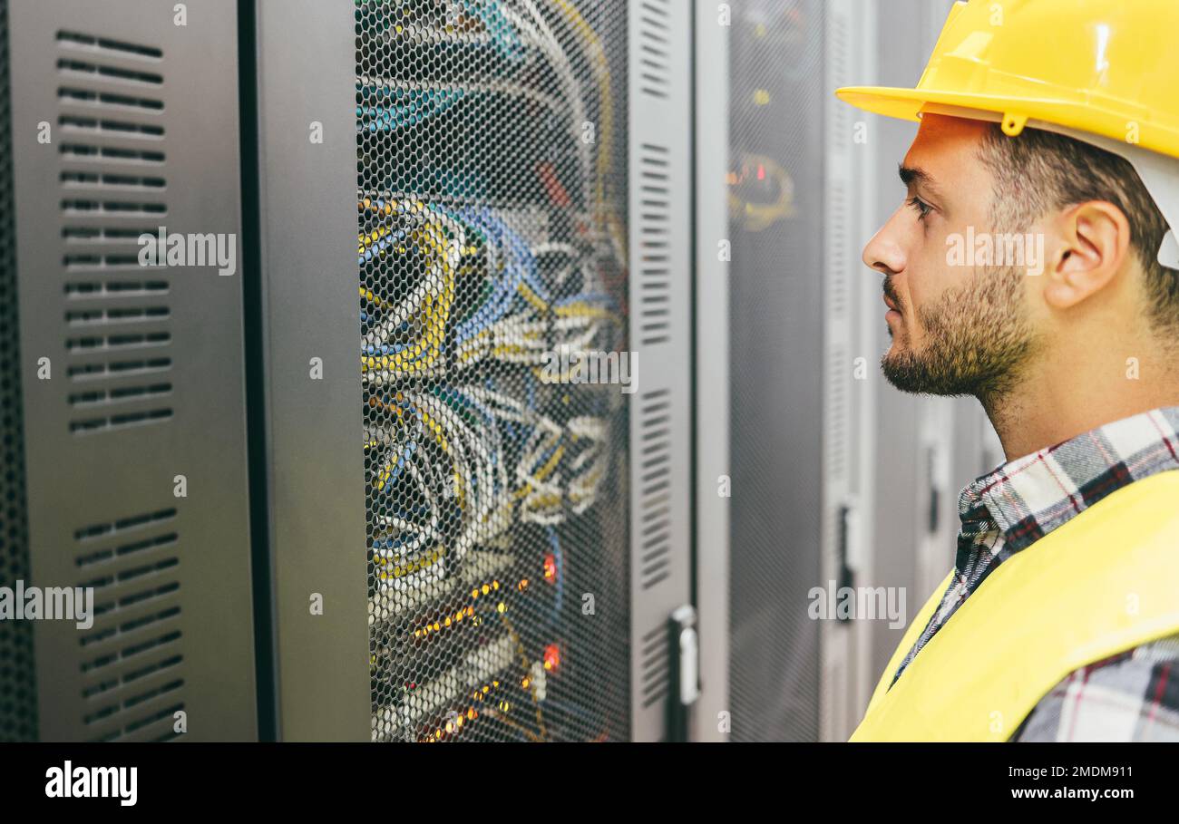 Young technician man working with inside big data center room - Focus ...