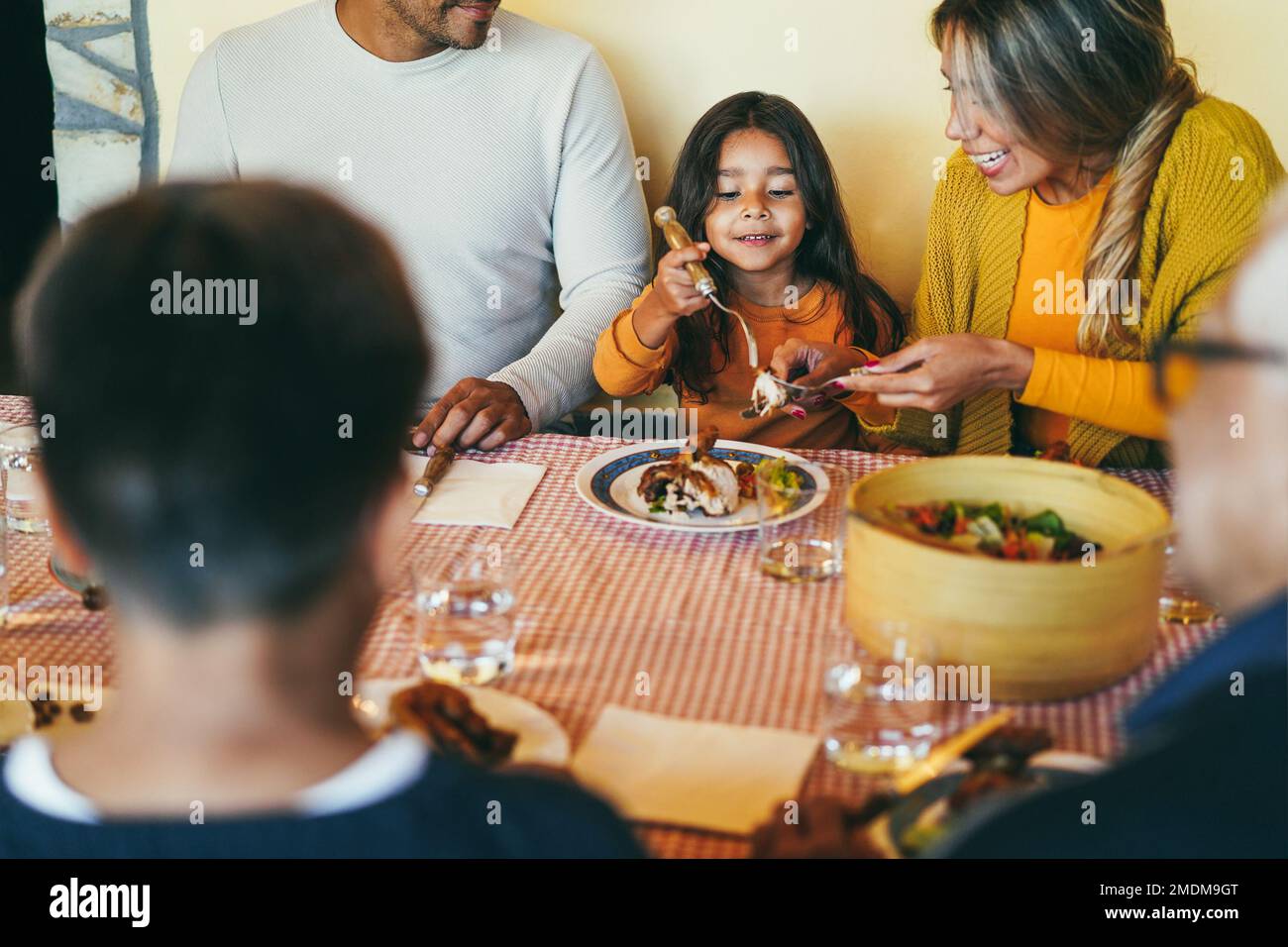 Latin parents having fun with children during home dinner - Focus on ...