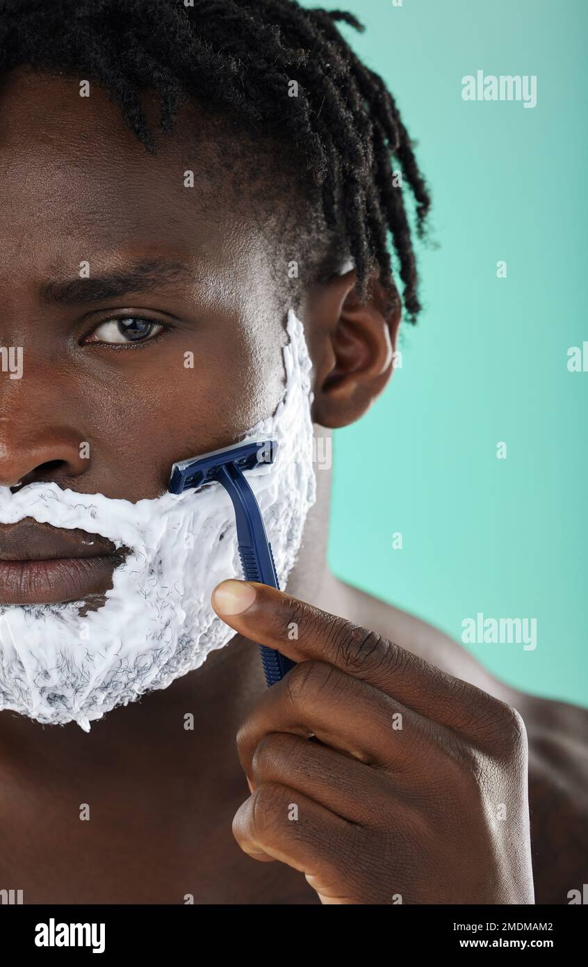 Black man, shaving and studio with skincare foam, razor and facial cosmetics for beauty by blue ...