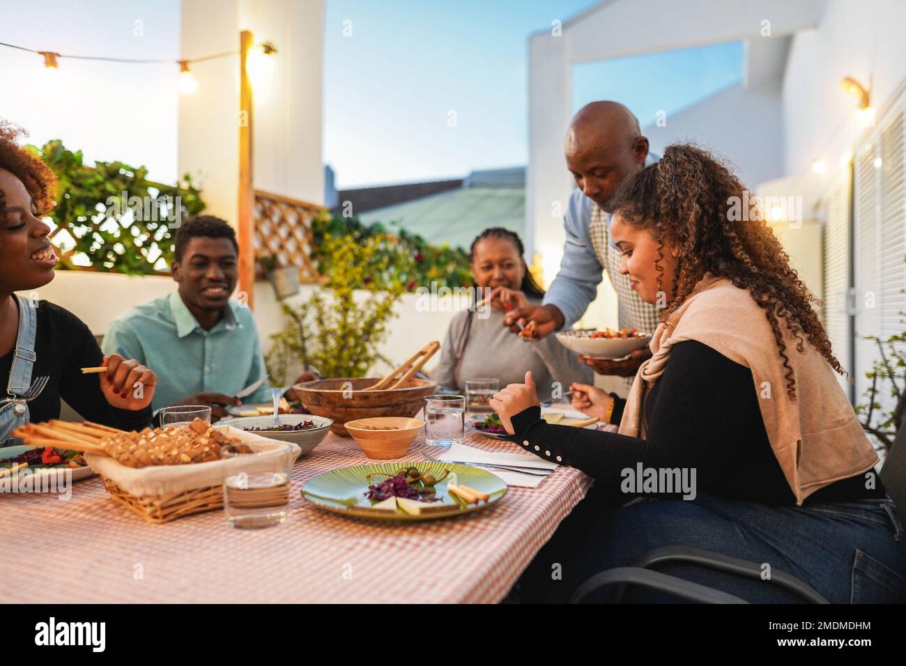 Happy african family doing dinner while eating healthy food at home ...