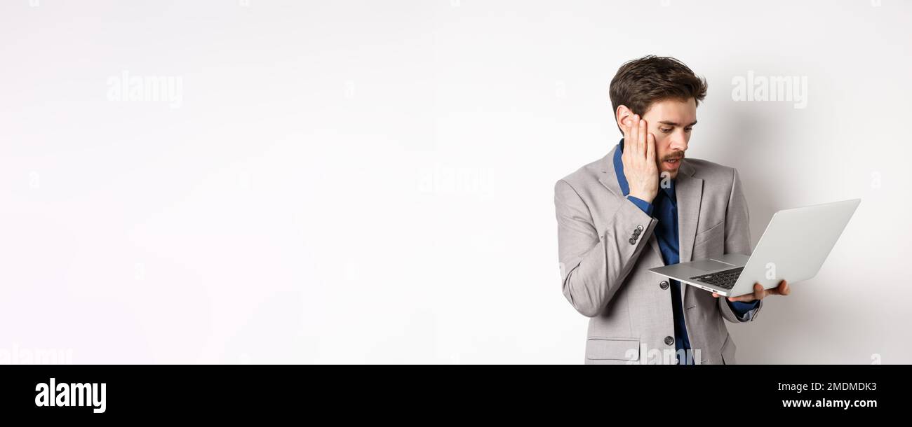 Shocked and worried businessman making mistake on laptop, looking at ...