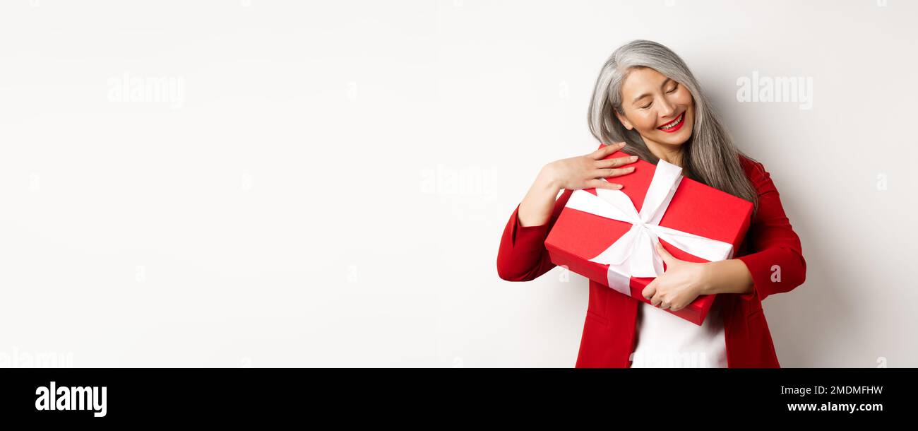 Valentine day concept. Beautiful asian senior woman hugging box with ...
