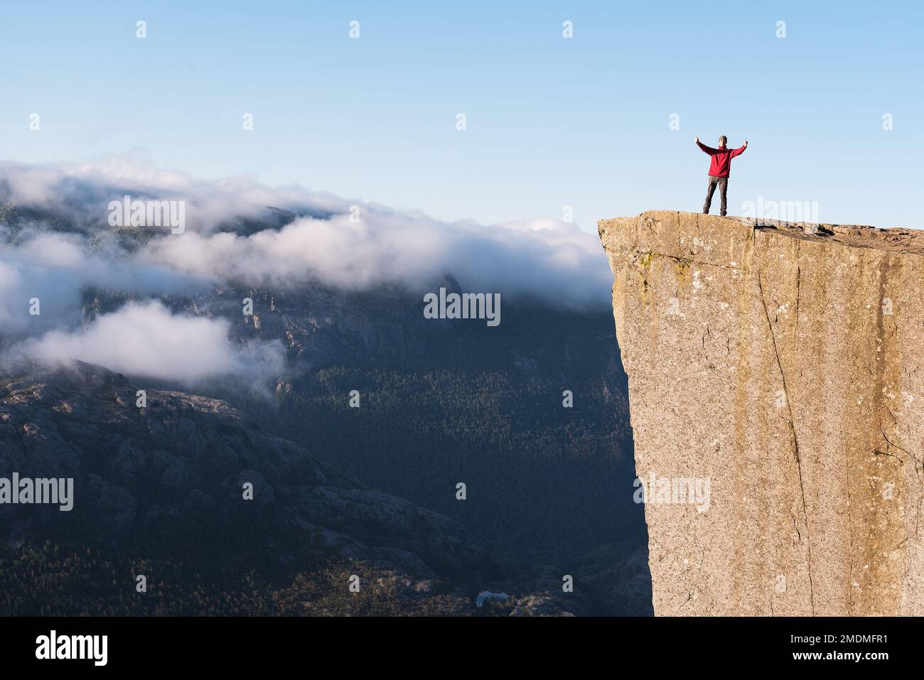 Preikestolen - amazing rock in Norway. Guy on a cliff above the clouds ...