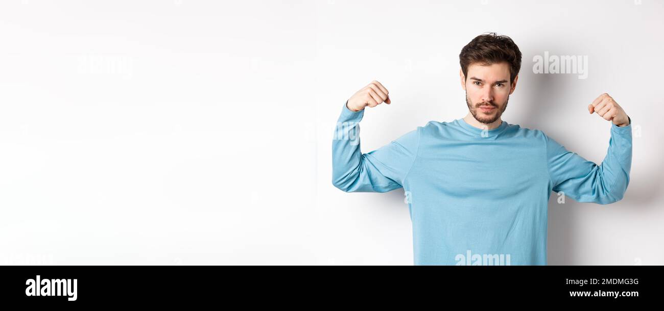 Confident and strong macho man flexing biceps, showing strength in ...