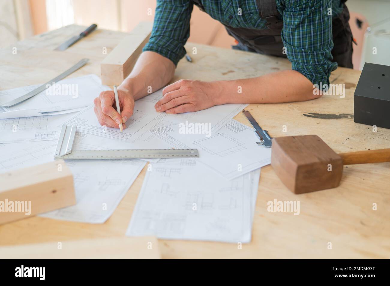 A portrait of a carpenter in goggles and work overalls draws a ...