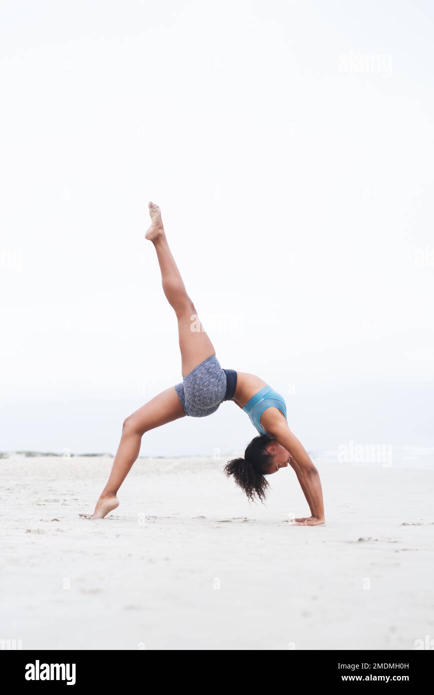 Theres strength and grace in her form. a young woman doing a handstand ...
