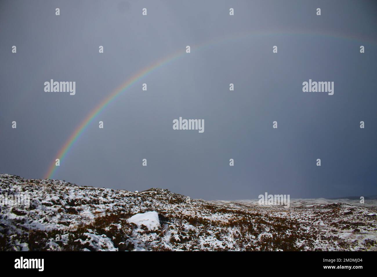 The rainbow and the cloudy sky over the snowy-peaked mountain Stock ...