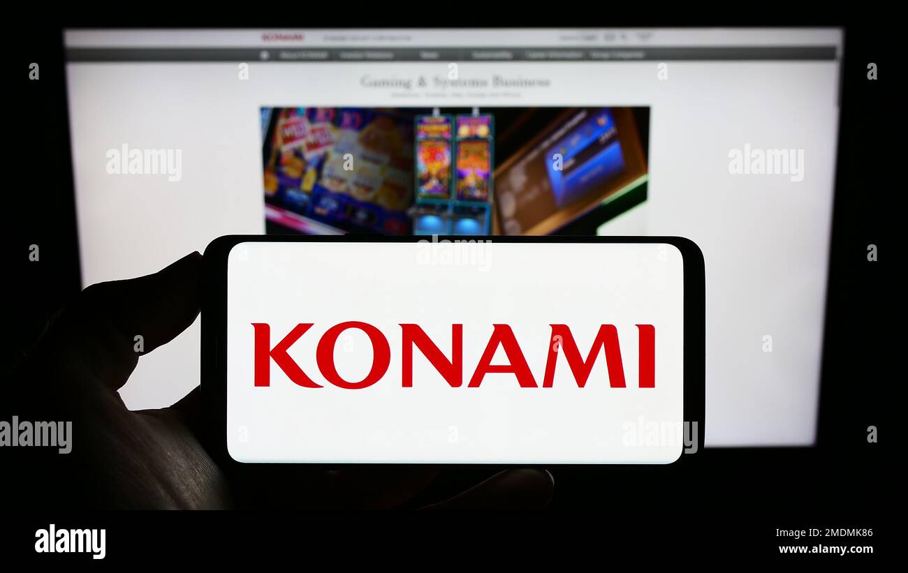 Person holding cellphone with logo of Japanese company Konami Group ...