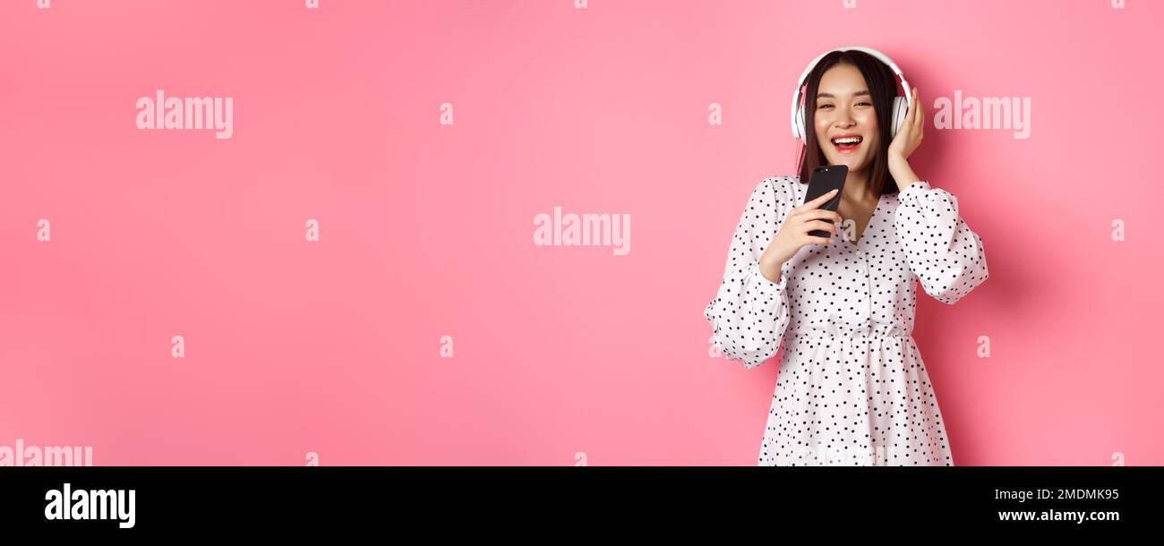 Beautiful smiling asian woman singing song in smartphone microphone ...