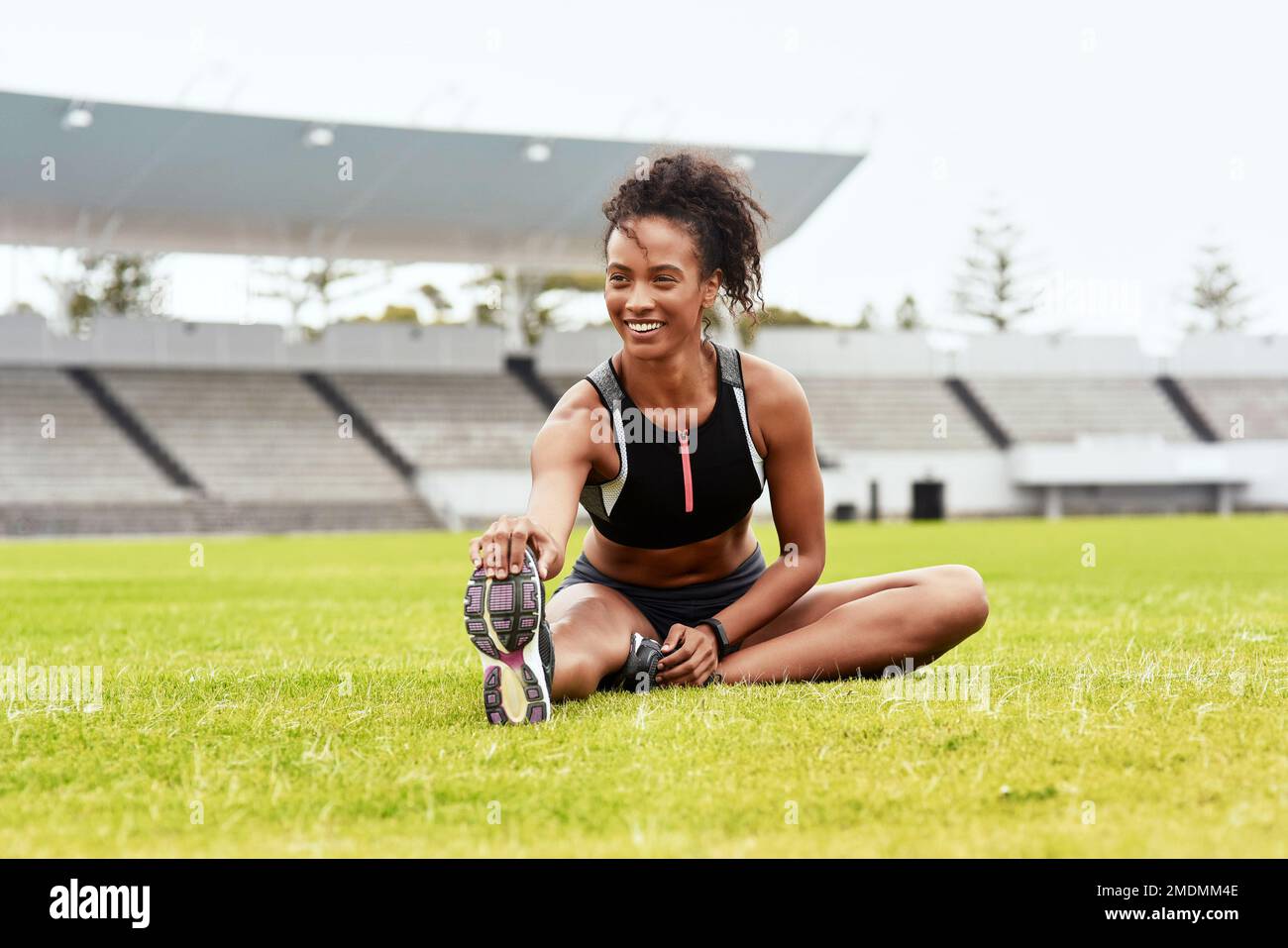 Stretching before her workout. Full length shot of an attractive young female athlete warming up ...
