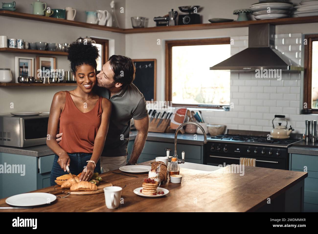 Im looking forward to take a bite. a man kissing his wife while she prepares breakfast in the ...
