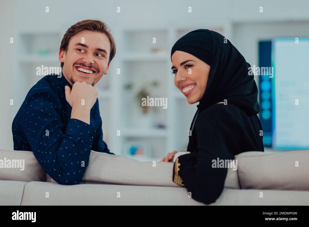 Young muslim couple woman wearing islamic hijab clothes sitting on sofa ...