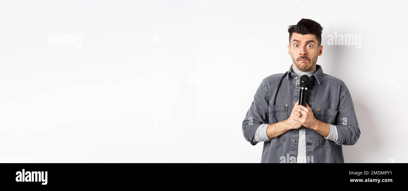 Nervous unconfident guy holding microphone and look indecisive, scared ...