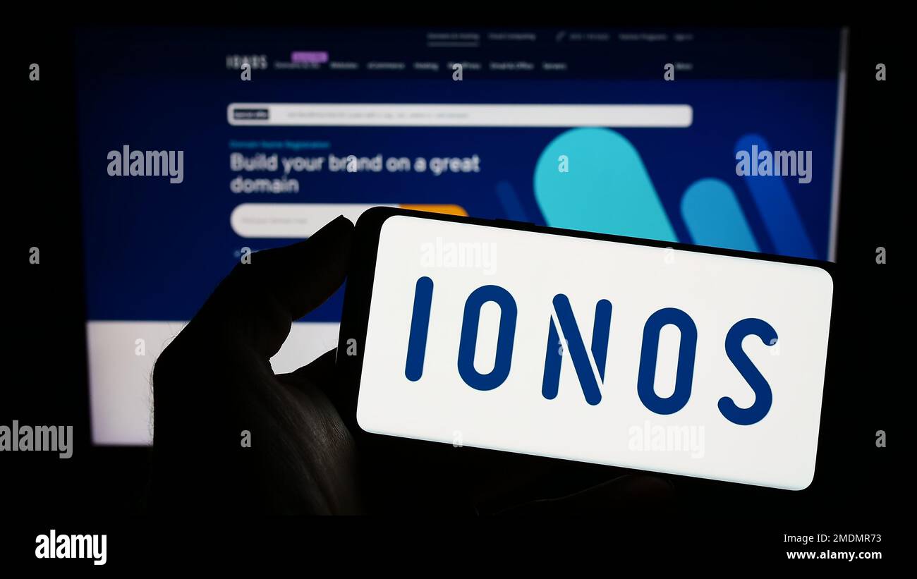 Person holding mobile phone with logo of German web hosting company ...