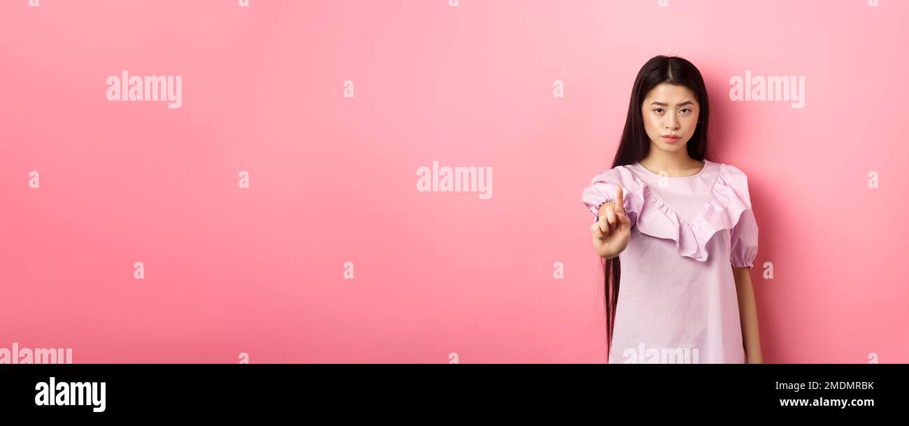 She says no. Serious asian girl shaking finger in stop gesture ...