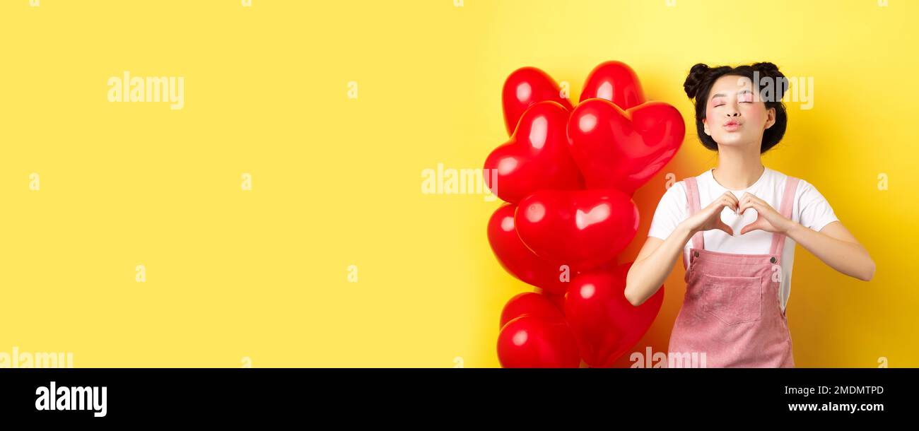 Romantic girl close eyes and pucker lips for kiss, showing I love you ...