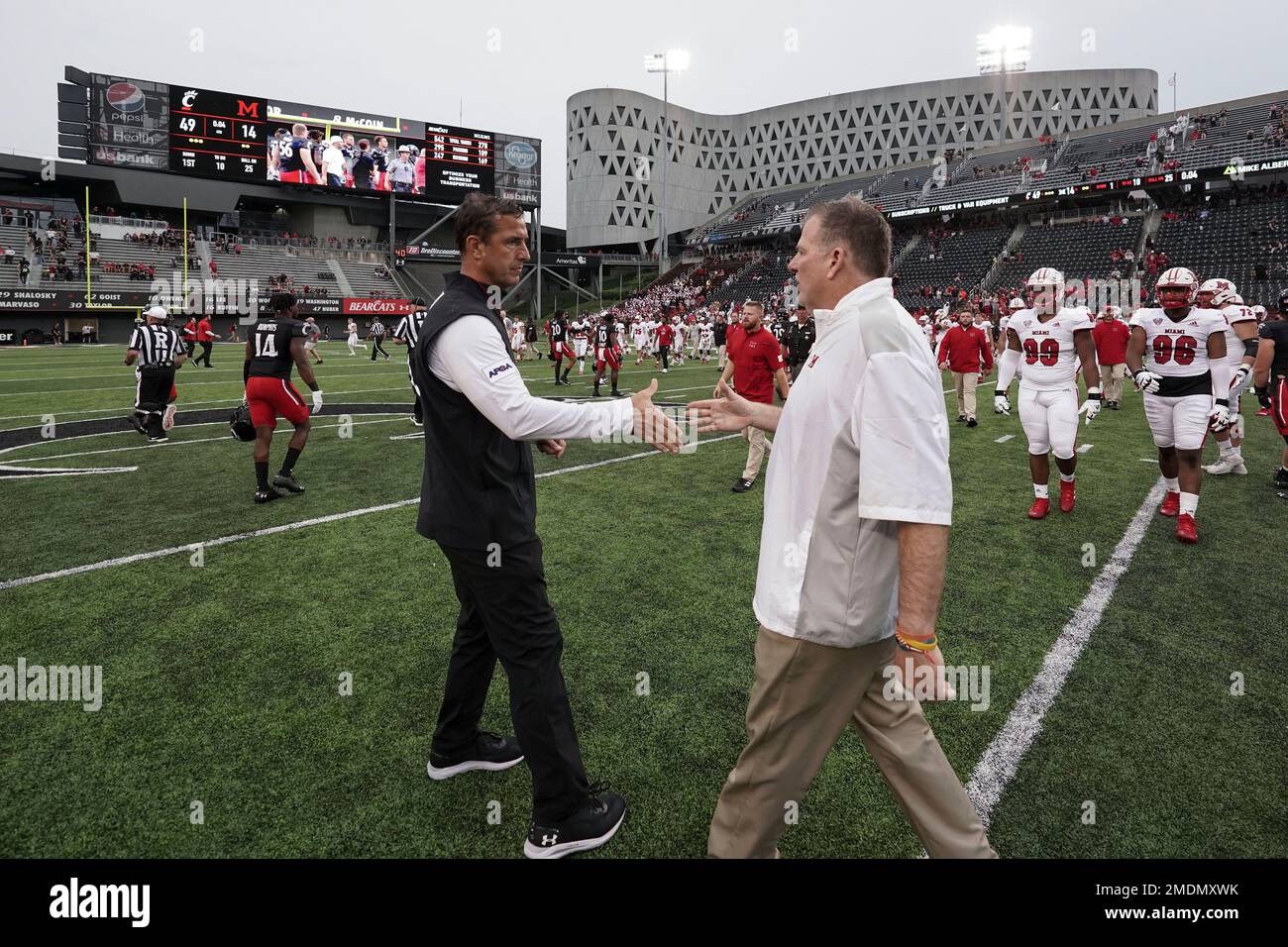 Cincinnati head coach, center left, shakes hands with Miami (Ohio) head ...