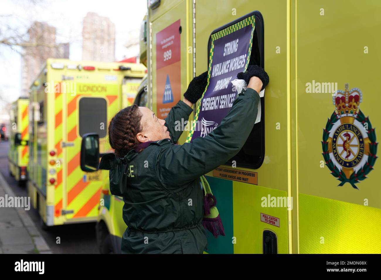 An ambulance worker placing a sign on the side of an stationery ...
