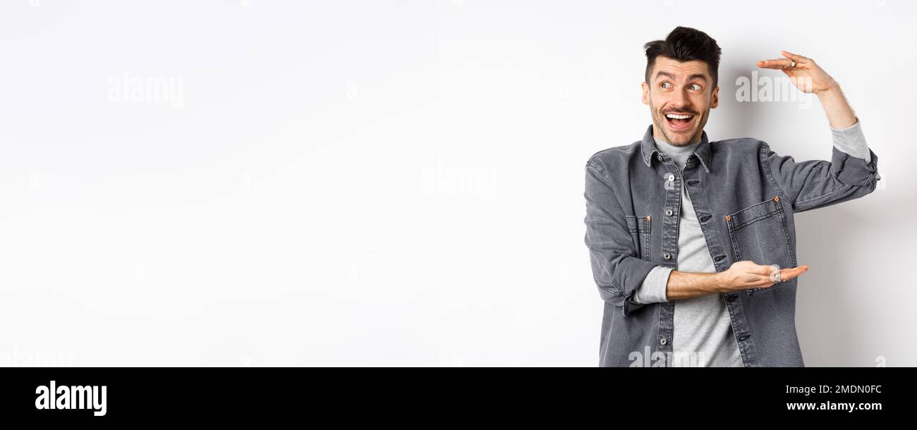 Excited guy looking at logo and showing big size thing, shaping large ...