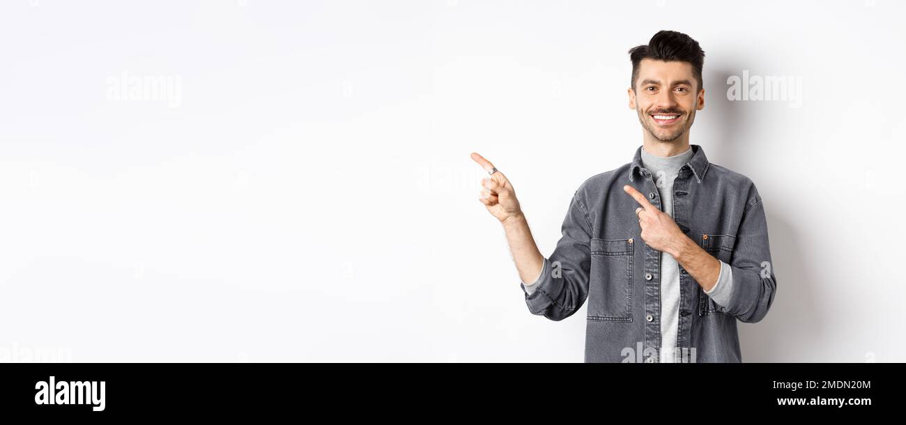 Handsome smiling man pointing fingers left, showing logo and looking ...