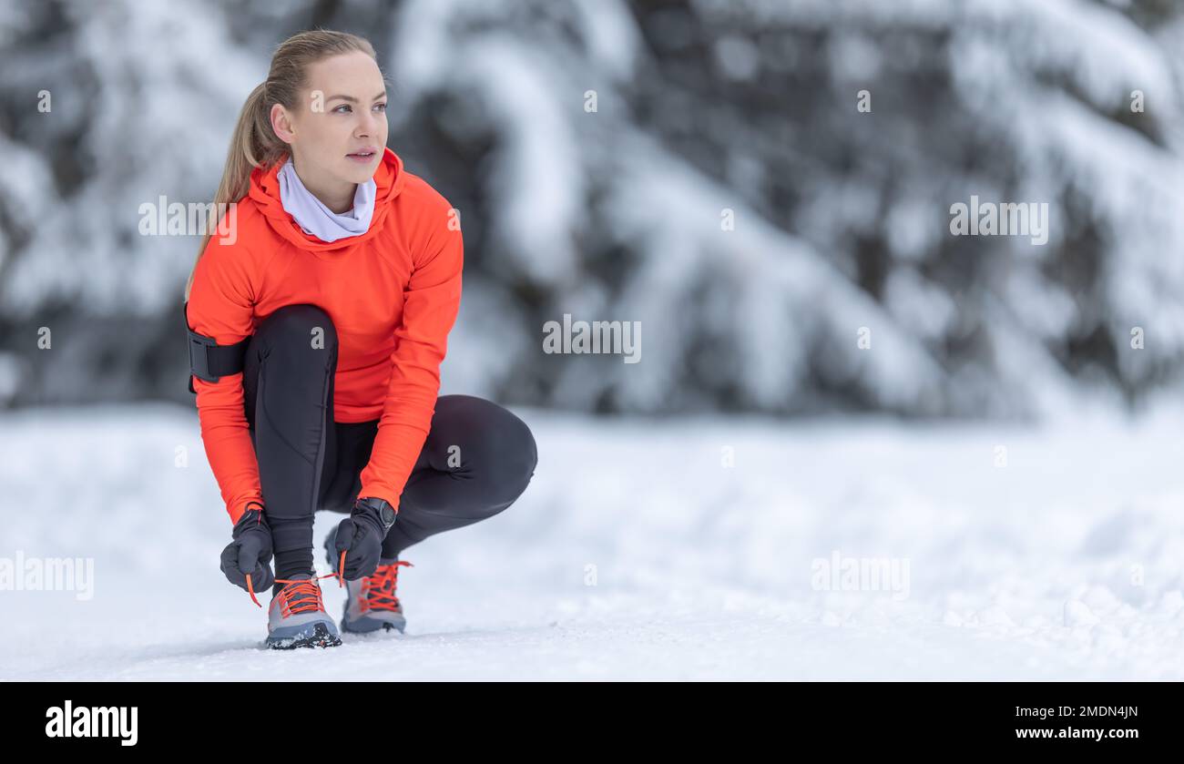 An attractive female runner is tying her shoelaces before training on ...