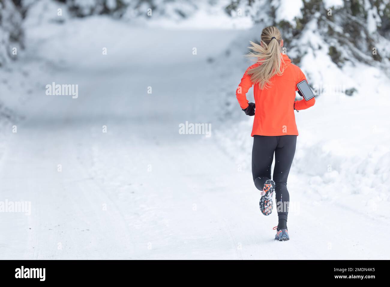 Running in winter, rear view of a female runner on a snowy path in a ...