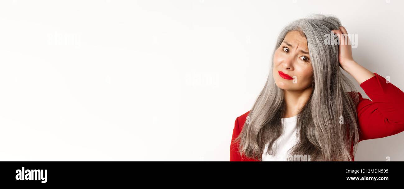 Close up portrait of confused asian female manager scratching head and ...