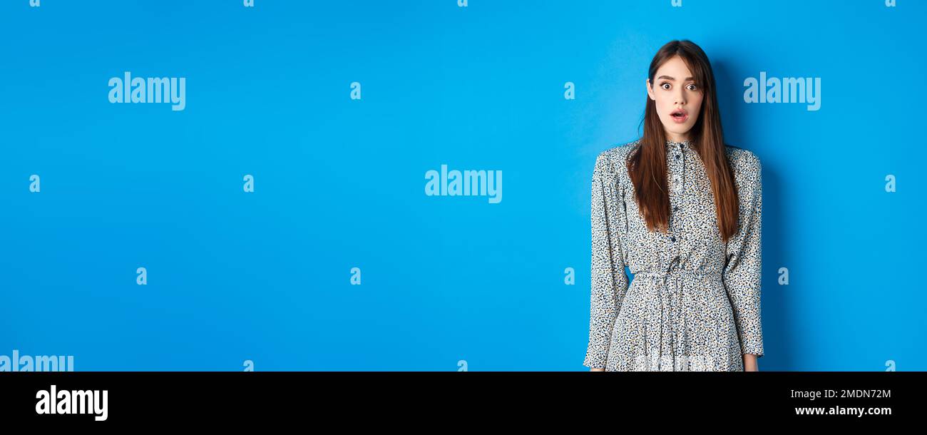 Shocked cute girl in dress looking at camera with opened mouth, gasping ...