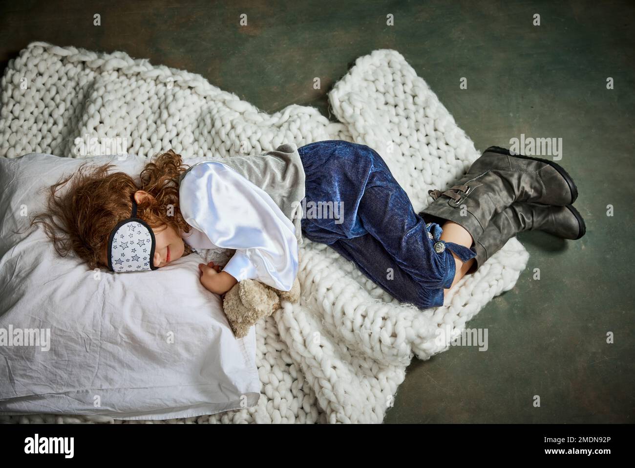 Ariel view of cute little girl in clothes sleeping on white blanket ...