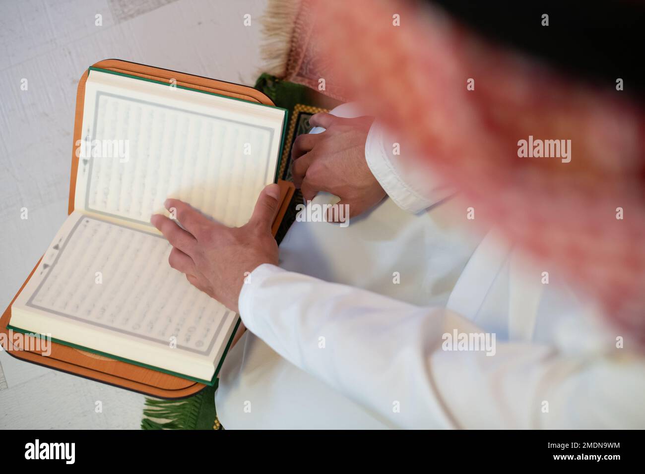 Young arabian muslim man in traditional clothes reading holy book Quran ...