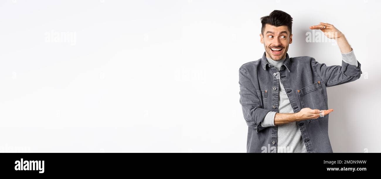 Excited guy looking at logo and showing big size thing, shaping large ...